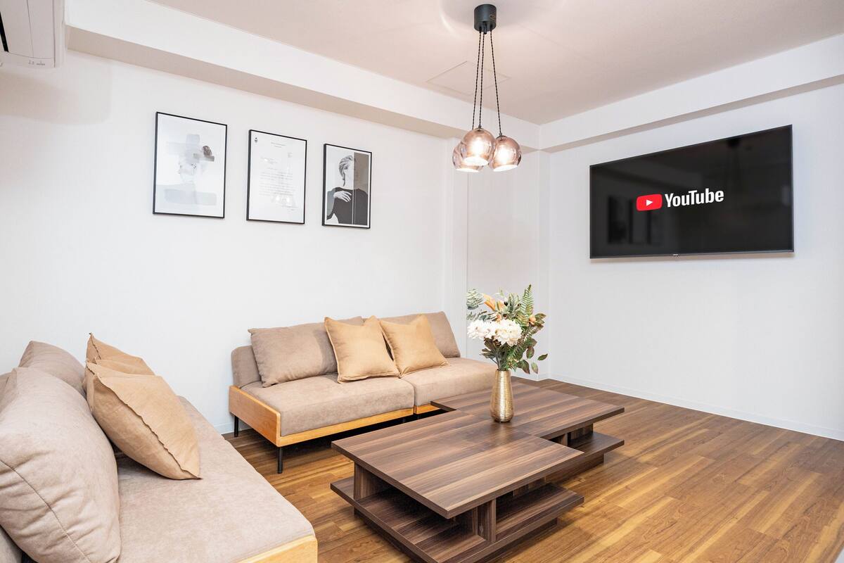 Uma sala de estar moderna com sofá, mesa de centro e televisão de tela plana na parede.