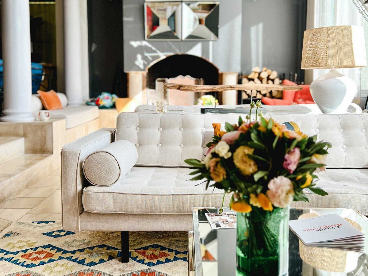 Uma sala de estar moderna com um sofá bege, uma mesa de centro de vidro e um vaso de flores.