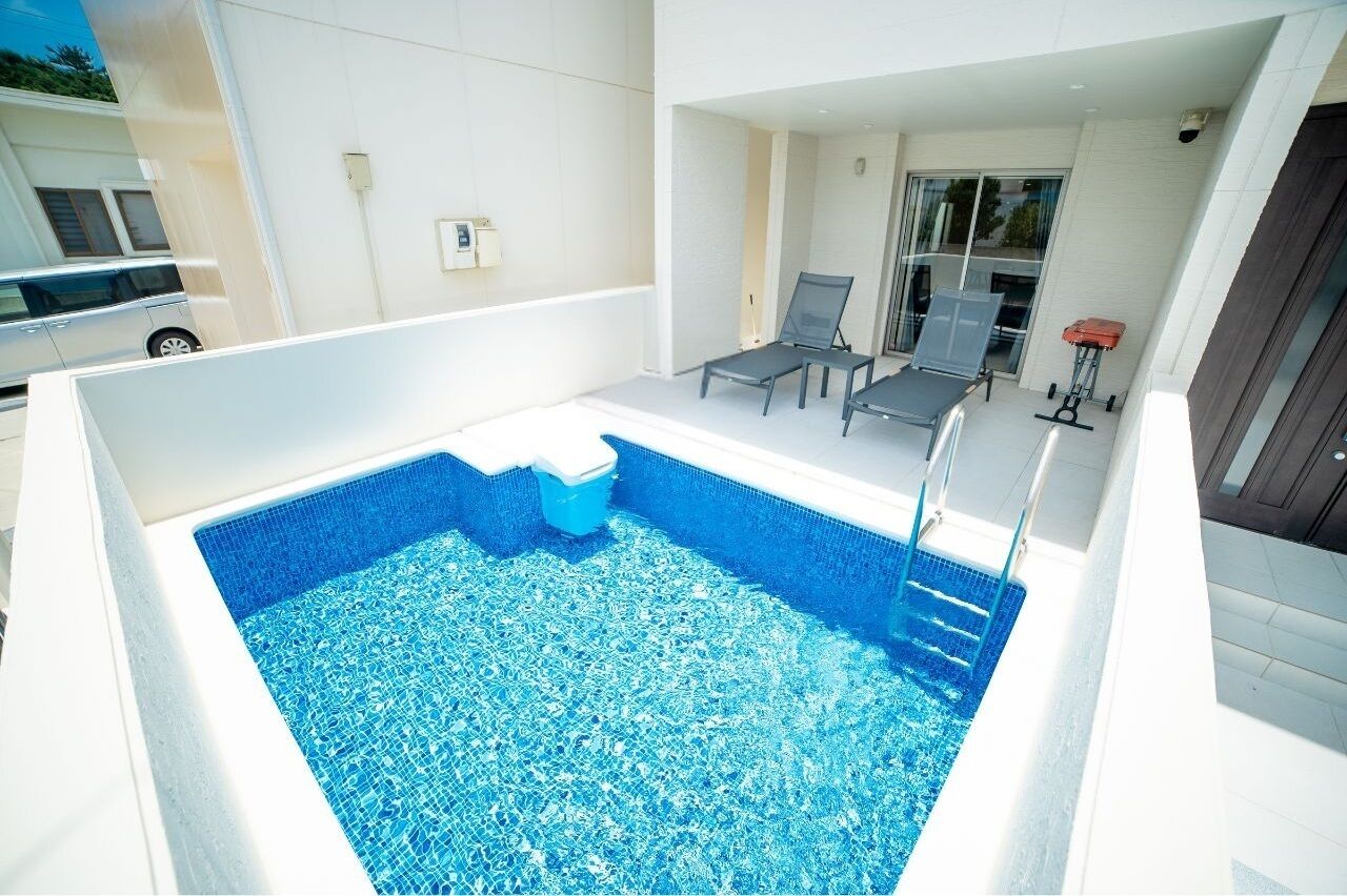 Piscina no terraço com cobertura de vidro, espreguiçadeiras e área para churrasco.