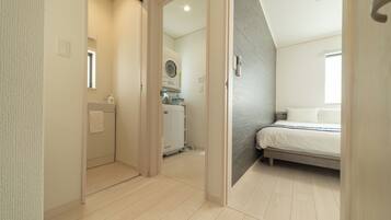 Quarto com cama, máquina de lavar e banheiro pequeno.
