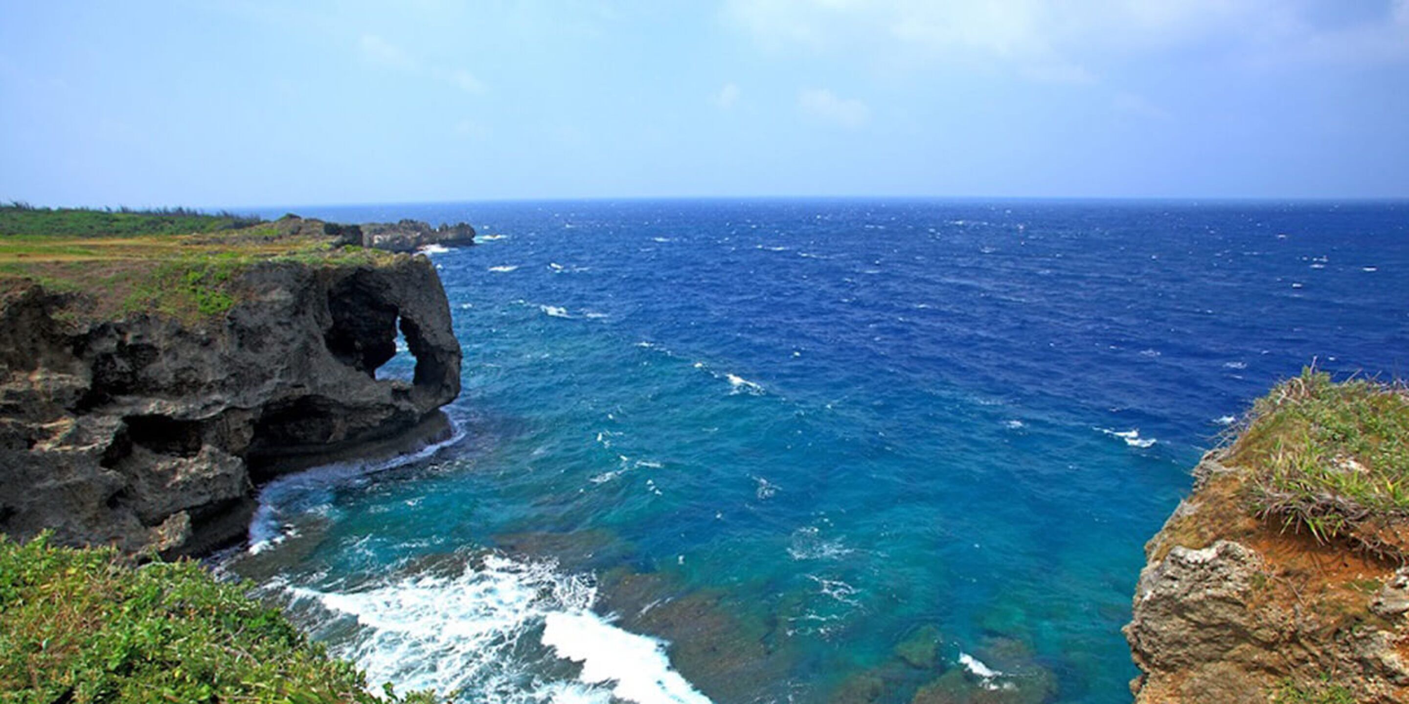Paisagem costeira com uma formação rochosa imponente e um arco natural.