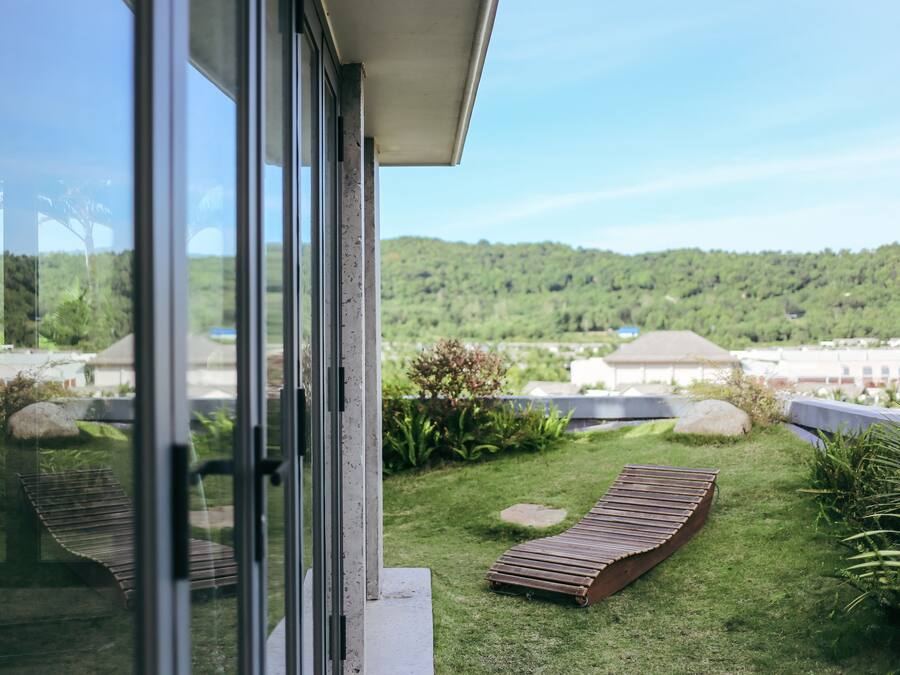 Vista de varanda com área gramada, deck de madeira e colina ao longe.