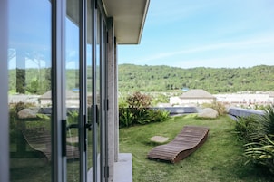 Vista de varanda com área gramada, deck de madeira e colina ao longe.