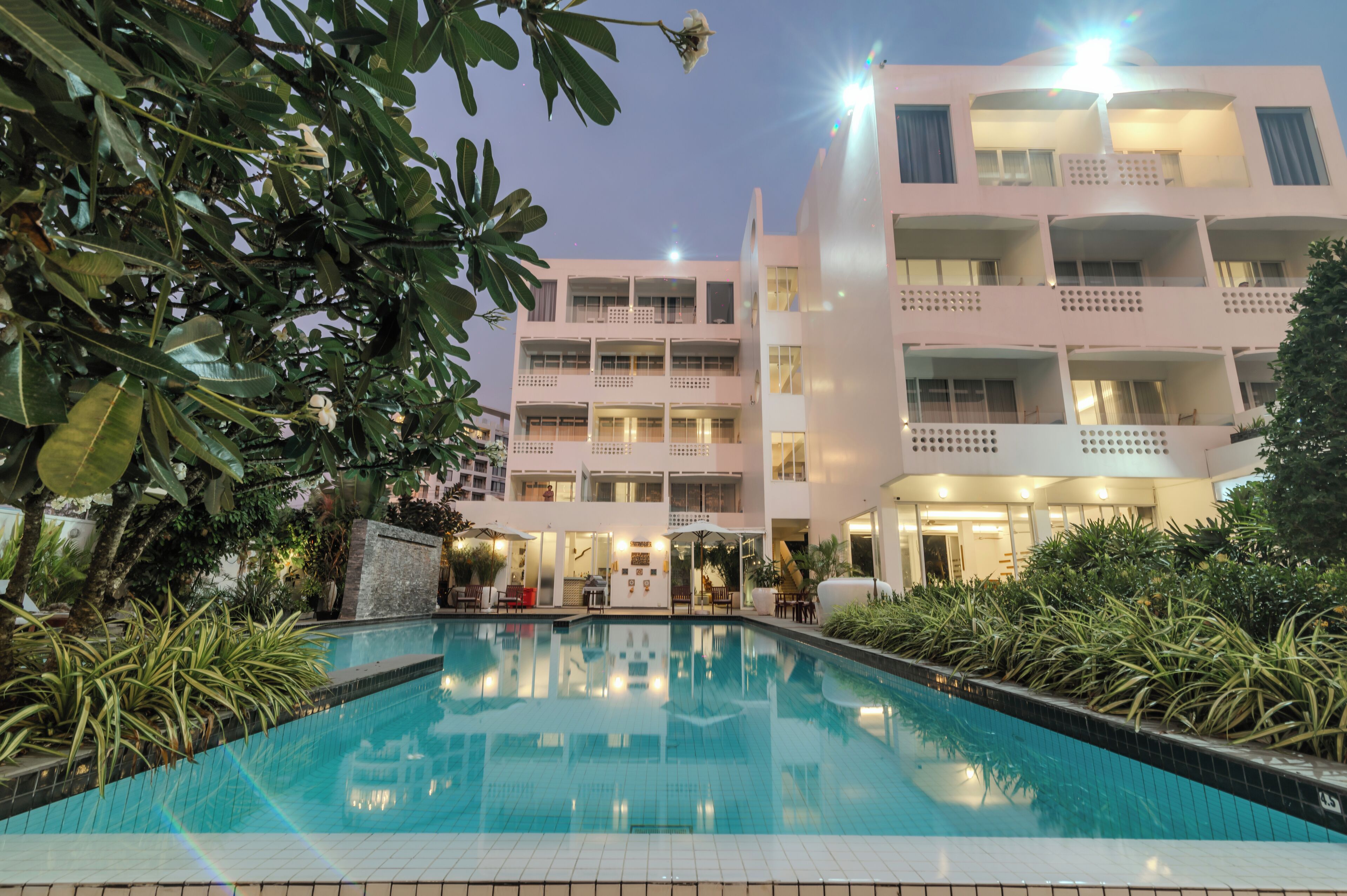 Hotel com piscina, várias varandas e vegetação exuberante.