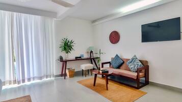 Uma sala de estar moderna com sofá, mesa de centro e TV fixada na parede.