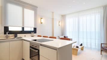 Cozinha moderna com ilha central, forno embutido e área de refeições com mesa e cadeiras.