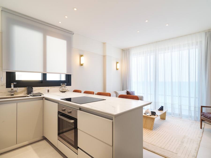 Cozinha moderna com ilha central, forno embutido e área de refeições com mesa e cadeiras.