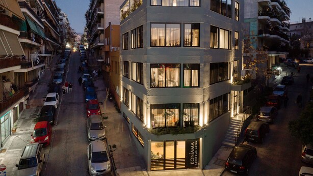 Um hotel com vários andares chamado "KONIAMA ACROPOLIS", com design arquitetônico moderno, apresentando varandas e grandes janelas.