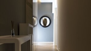 Corredor moderno com uma mesa de recepção, um espelho redondo e um lustre no teto.
