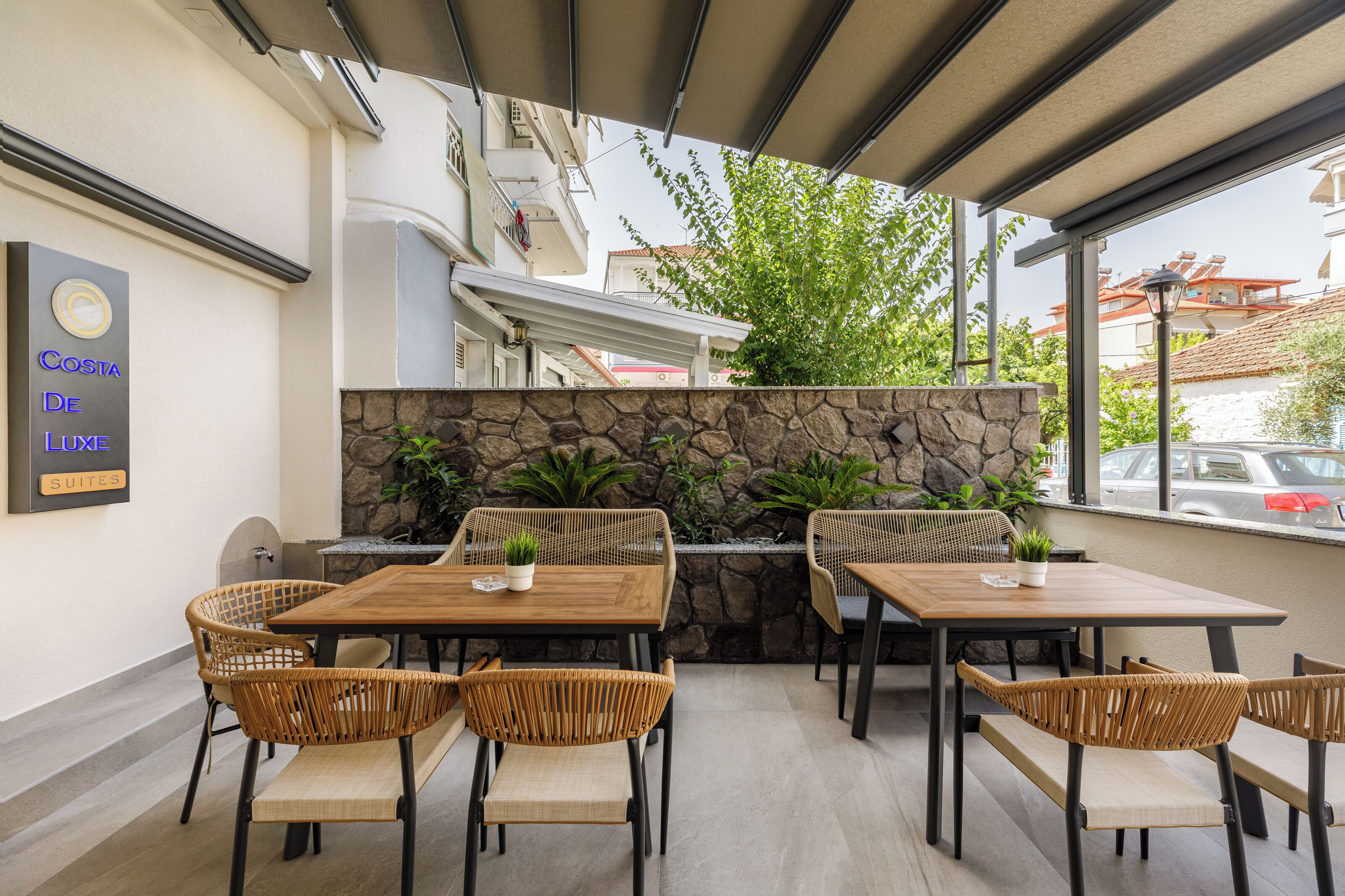 Restaurante com mesas ao ar livre, paredes de pedra e vasos de plantas.