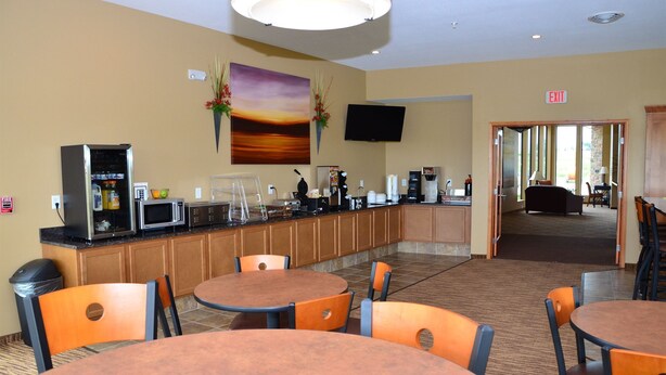 Um saguão de hotel com um espaço de café, área de estar e uma TV fixada na parede.
