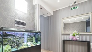 Uma casa de banho moderna com um aquário grande, um espelho e uma pequena mesa com um arranjo floral.