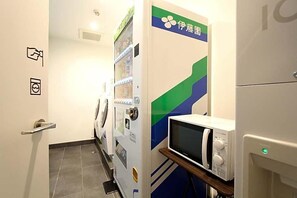 Quarto de hotel com máquina de lavar, micro-ondas e porta com design verde e azul.