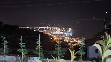 Vista noturna de uma cidade com edifícios iluminados e uma ponte ao longe.