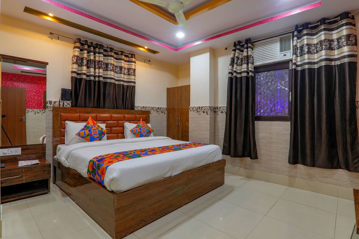 Quarto moderno com cama de madeira, mesa de cabeceira, guarda-roupa e janela com cortinas.
