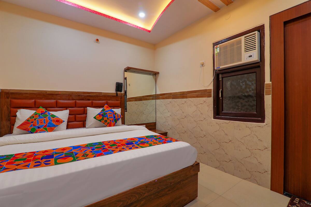 Quarto com cama, mesa de cabeceira, espelho e ar condicionado.