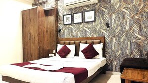 Quarto bem arrumado com cama, guarda-roupa de madeira e papel de parede estampado.