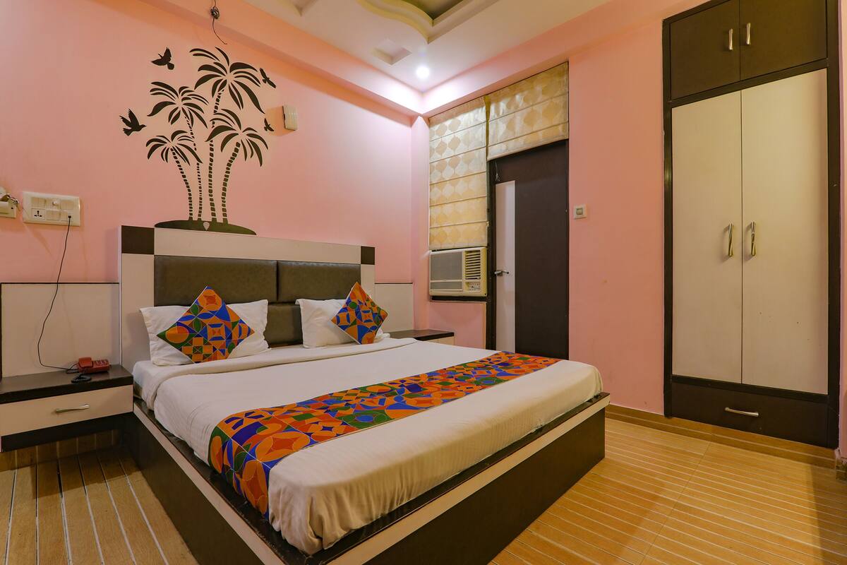 Quarto de hotel com cama, mesa de cabeceira, guarda-roupa e decoração na parede.
