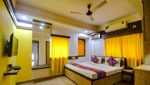 Quarto de hotel com cama, mesa de cabeceira, ventilador de teto.