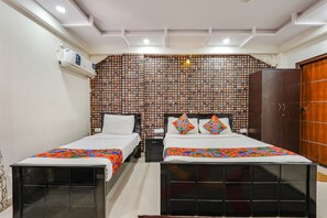 Quarto de hotel com duas camas, um guarda-roupa e parede estampada.
