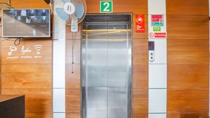 Um elevador com um painel digital, um ventilador e uma placa indicando o segundo andar.