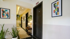 Um corredor com plantas em vasos, quadros nas paredes e piso coberto de carpete.