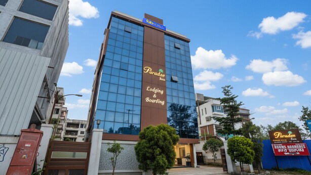Um edifício moderno de hotel com fachada de vidro, chamado 'Paradise Jus', oferecendo serviços de 'Lodging & Boarding'.