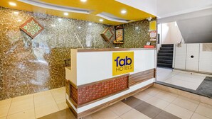 Uma área de recepção de hotel com uma parede de mármore, um balcão e uma escadaria.