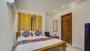 Quarto bem arrumado com uma cama de madeira, uma mesinha com chaleira e um espelho na parede.