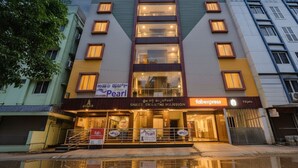 Um hotel com vários andares, um destaque com o letreiro 'Pearl' e uma placa 'fabexpress' indicando um serviço de transporte próximo.