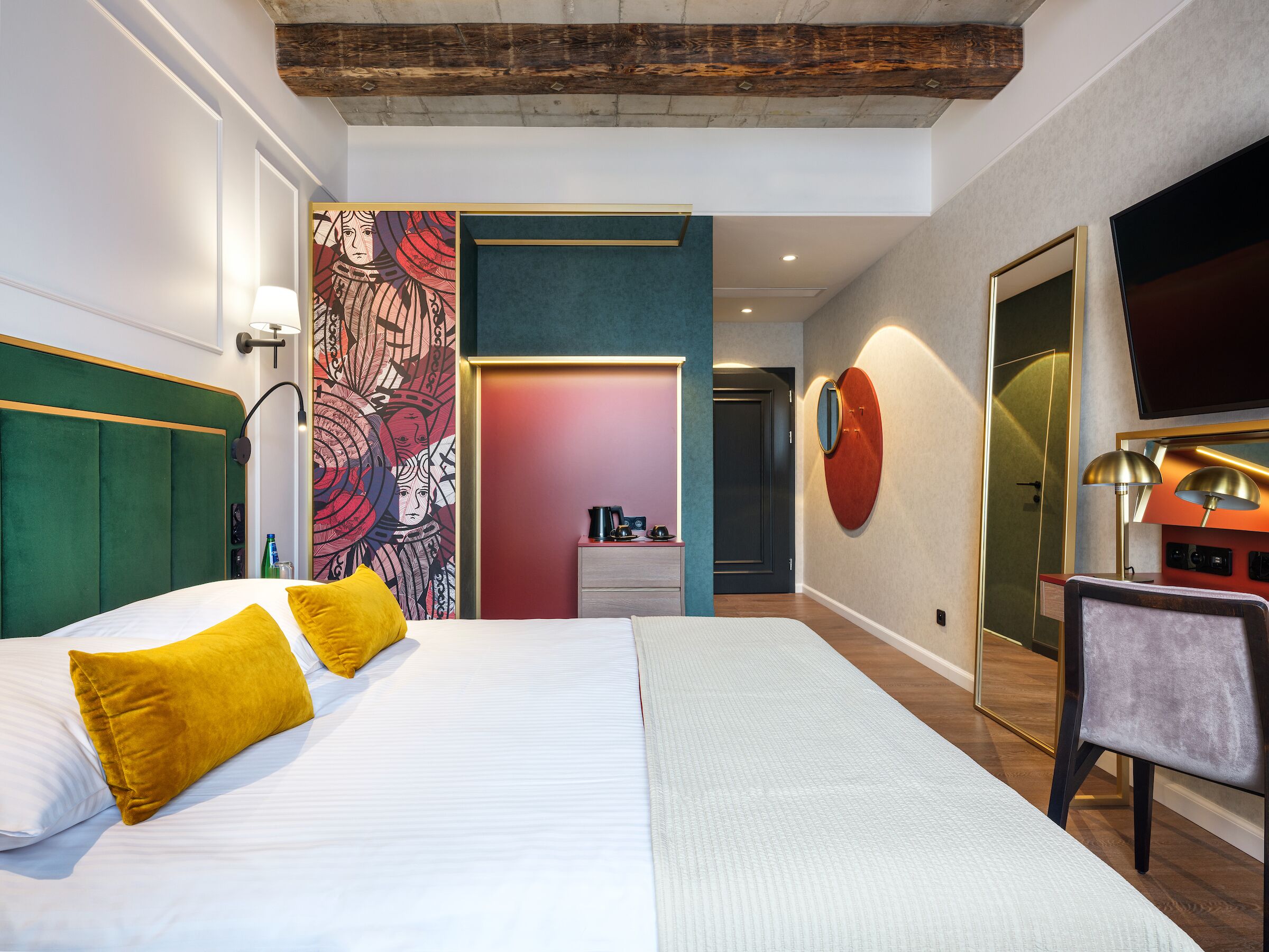 Quarto de hotel com uma cama grande, uma escrivaninha, uma cadeira e uma televisão.
