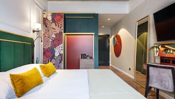 Quarto de hotel com uma cama grande, uma escrivaninha, uma cadeira e uma televisão.