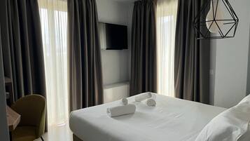 Quarto de hotel com cama, televisão na parede e uma cadeira.