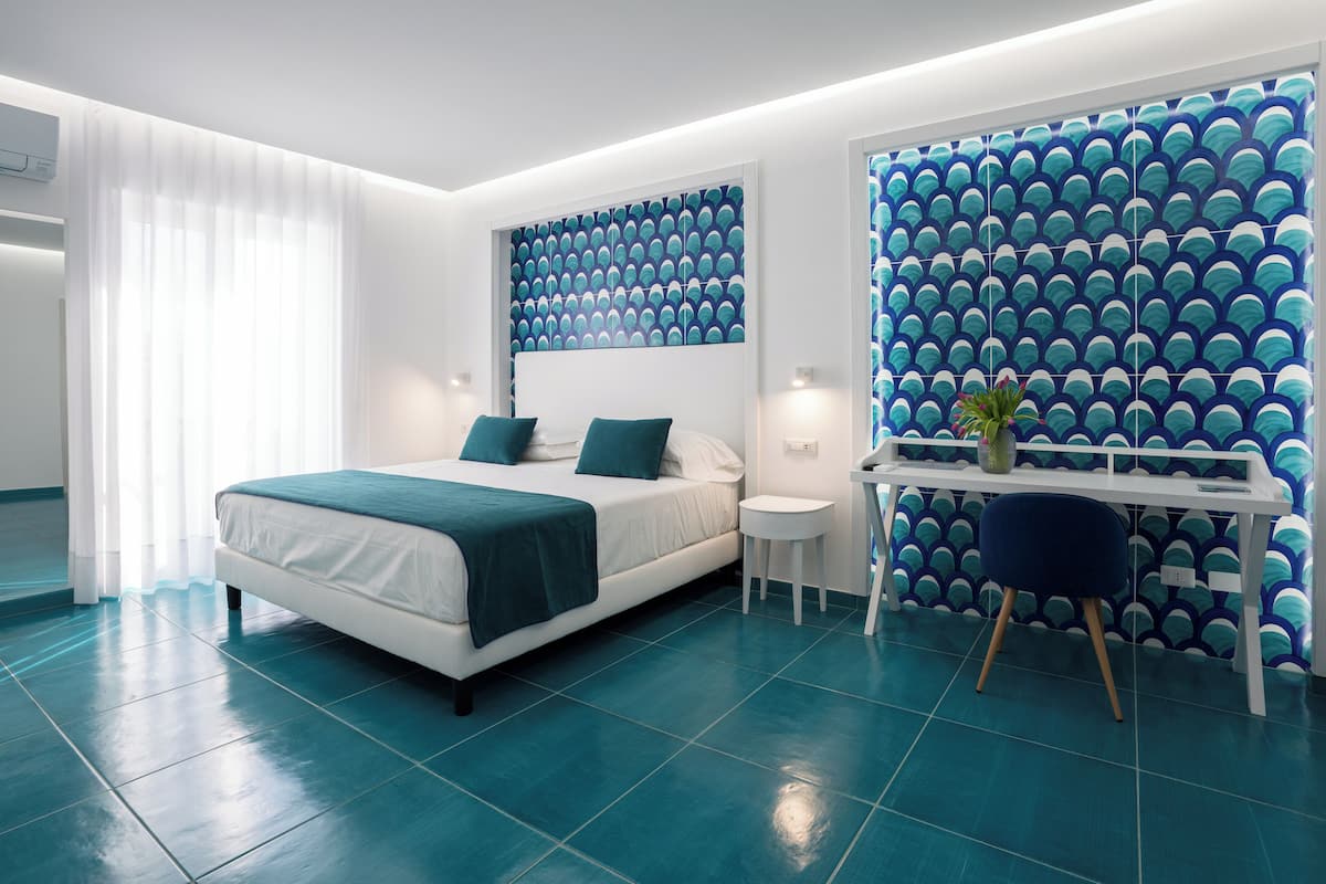 Quarto moderno com uma cama, uma escrivaninha e parede estampada.