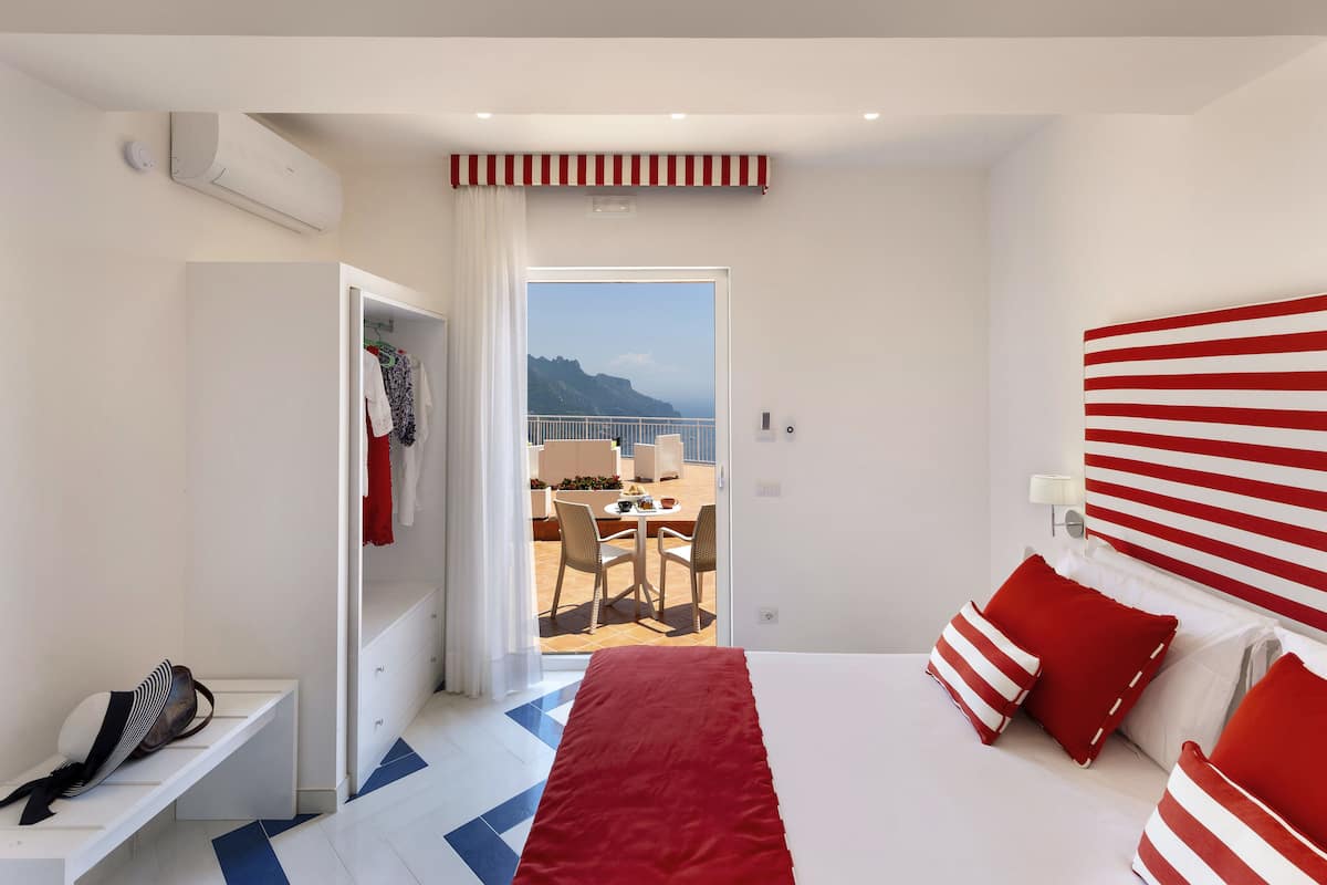 Quarto de hotel com cama, guarda-roupa, secretária e vista para o exterior.