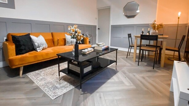 Sala moderna com sofá, mesa de centro e área de jantar.