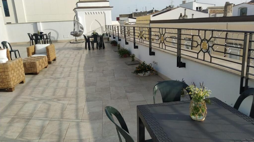 Terraço no telhado com área de estar ao ar livre, um ventilador e uma parede decorativa.