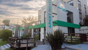 Um hotel moderno com um grande letreiro 'Apart Hotel', apresentando um esquema de cores verde e branco e um letreiro visível do restaurante 'Altoos Valeria Restaurante'.