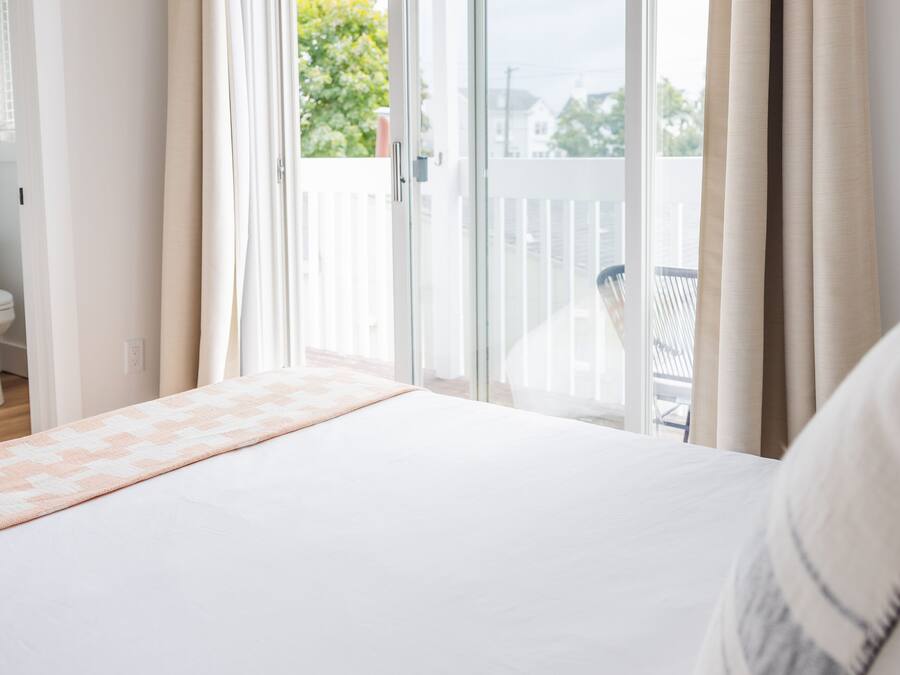 Quarto com uma grande porta de vidro deslizante que dá para uma varanda.