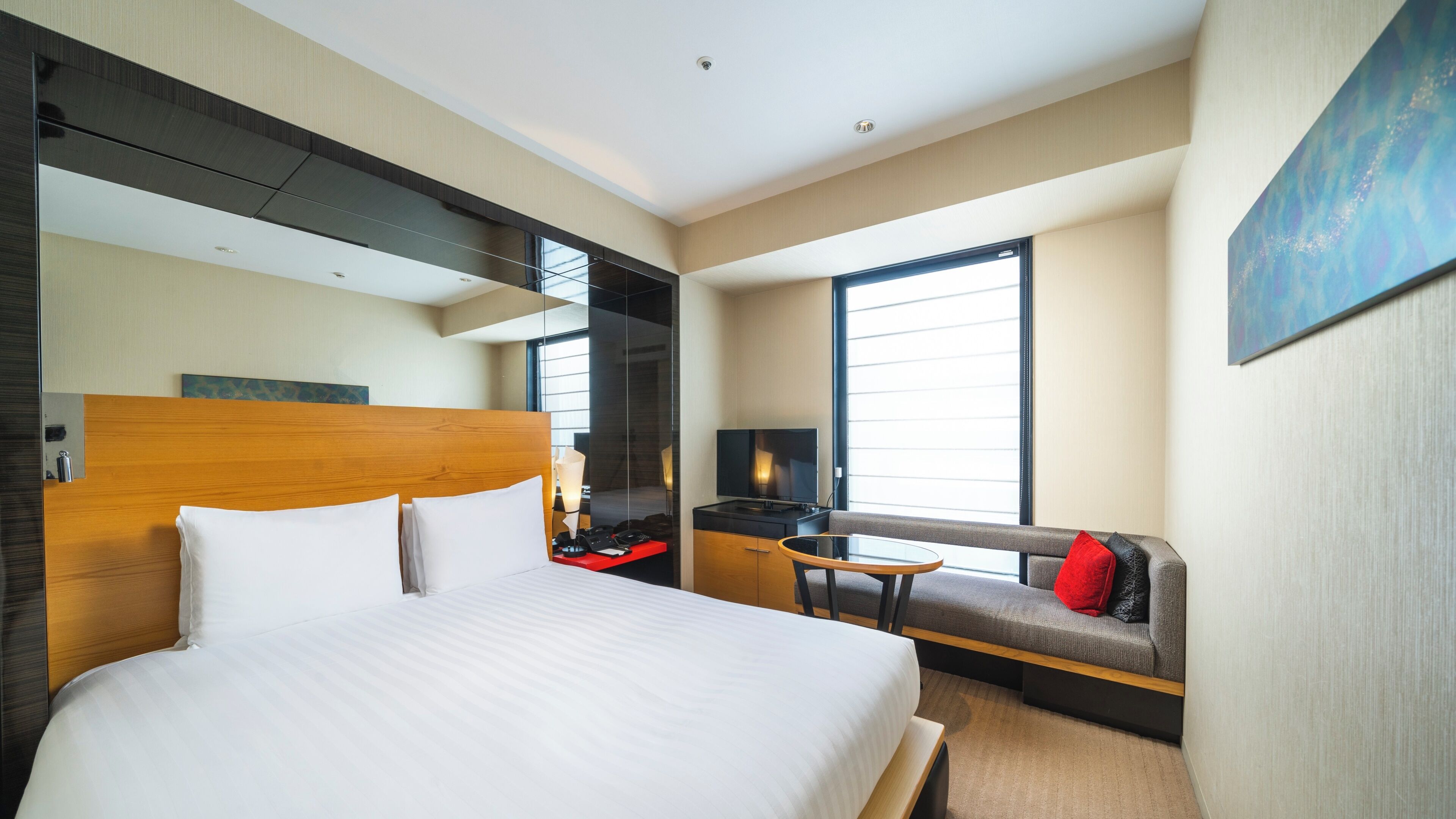 Quarto de hotel com uma cama grande, televisão, sofá e escrivaninha com cadeira.