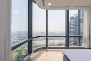 Quarto de hotel moderno em um prédio alto, com uma grande janela e vista para a cidade.