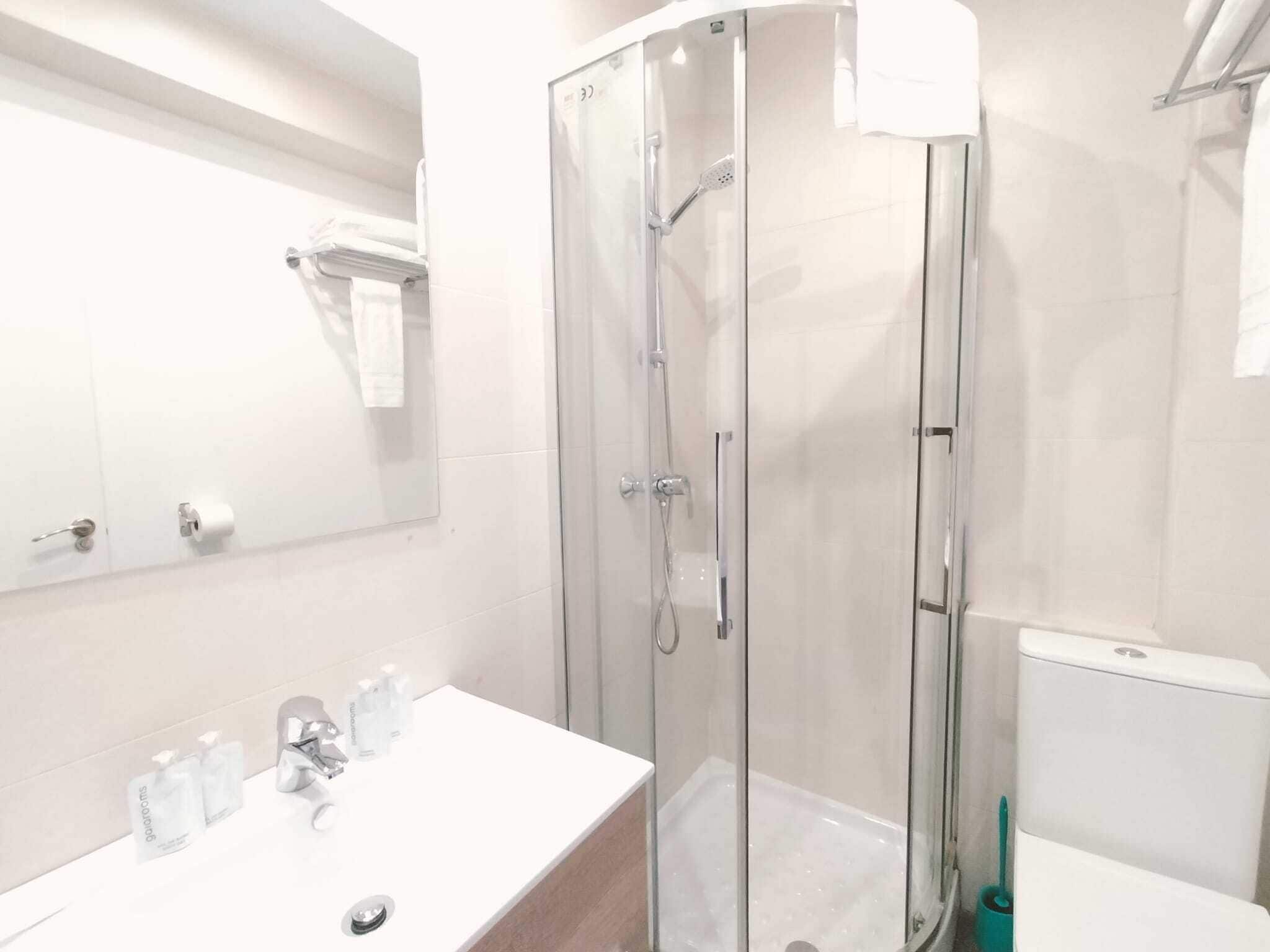 Uma casa de banho moderna com cabine de duche em vidro, lavatório branco e sanita.