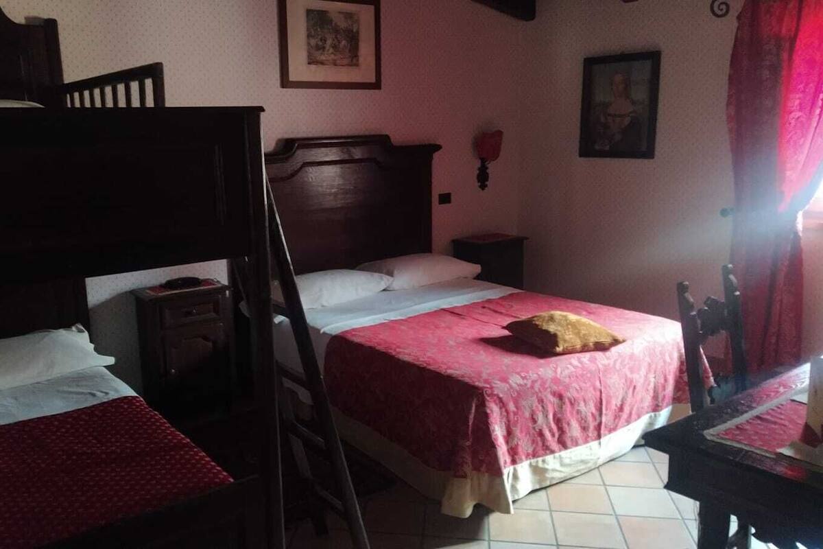 Quarto com duas beliches, cabeceira de madeira, mesa de cabeceira e um criado-mudo pequeno.