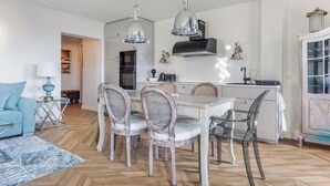Cozinha moderna com área de jantar, com mesa branca, cadeiras e luminárias pendentes.