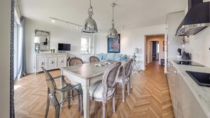 Uma cozinha ampla com área de jantar, piso em padrão herringbone de madeira e eletrodomésticos modernos.