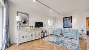 Uma sala de estar moderna com um armário branco, uma TV de tela plana, um sofá azul e um quadro abstrato grande.