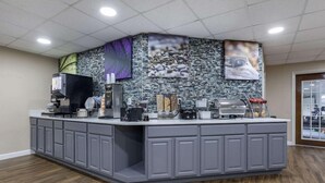 Uma área de recepção com balcão, máquinas de café e uma parede decorativa.