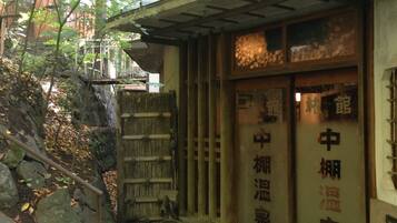 Um edifício tradicional japonês com entrada de madeira e degraus de pedra que o levam.