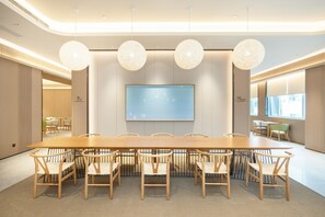 Uma sala de conferências com uma mesa comprida, seis cadeiras e três grandes luminárias pendentes esféricas.