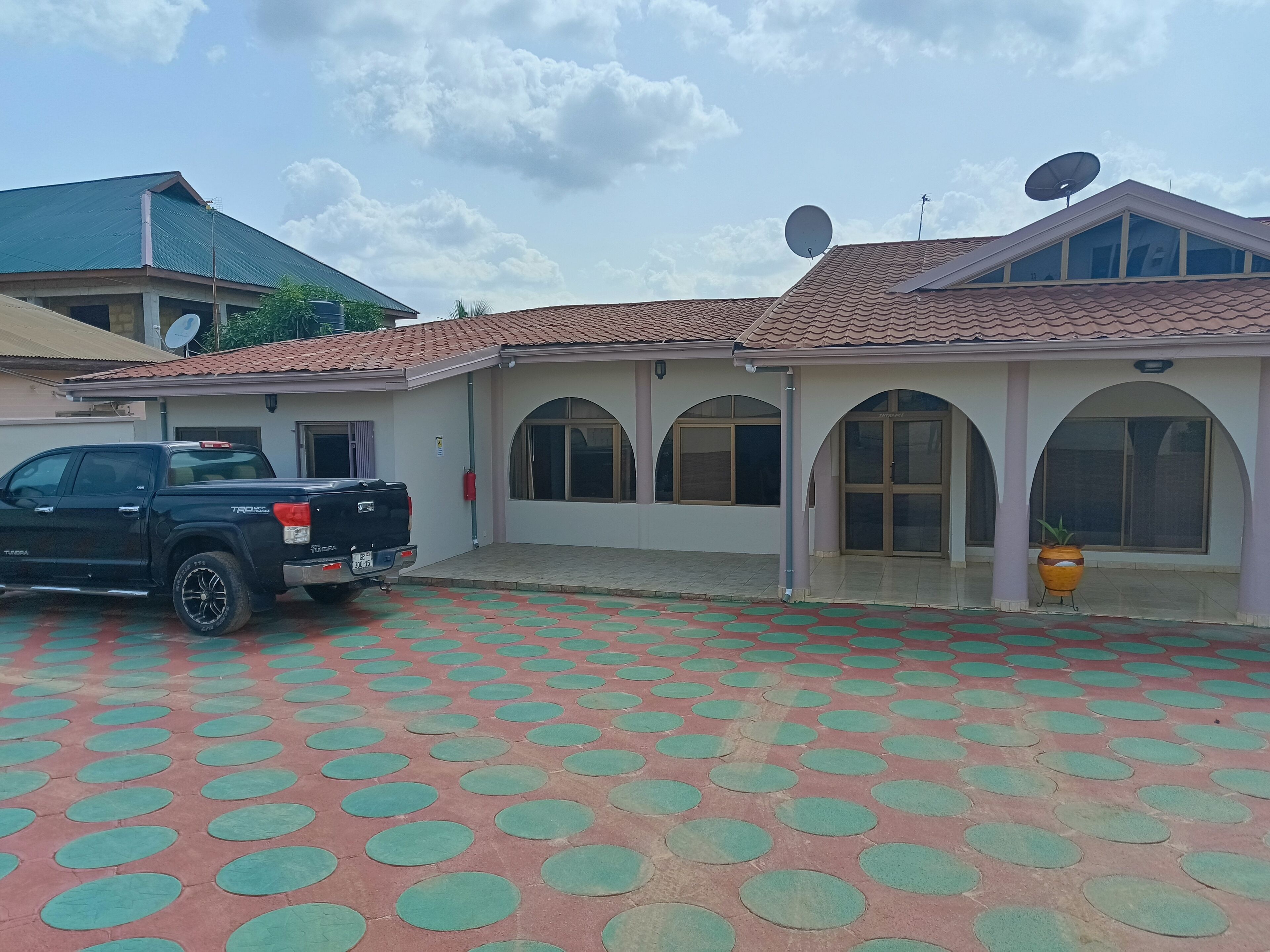 Um edifício com telhado telhado, antenas parabólicas e um espaço pavimentado com padrões circulares.